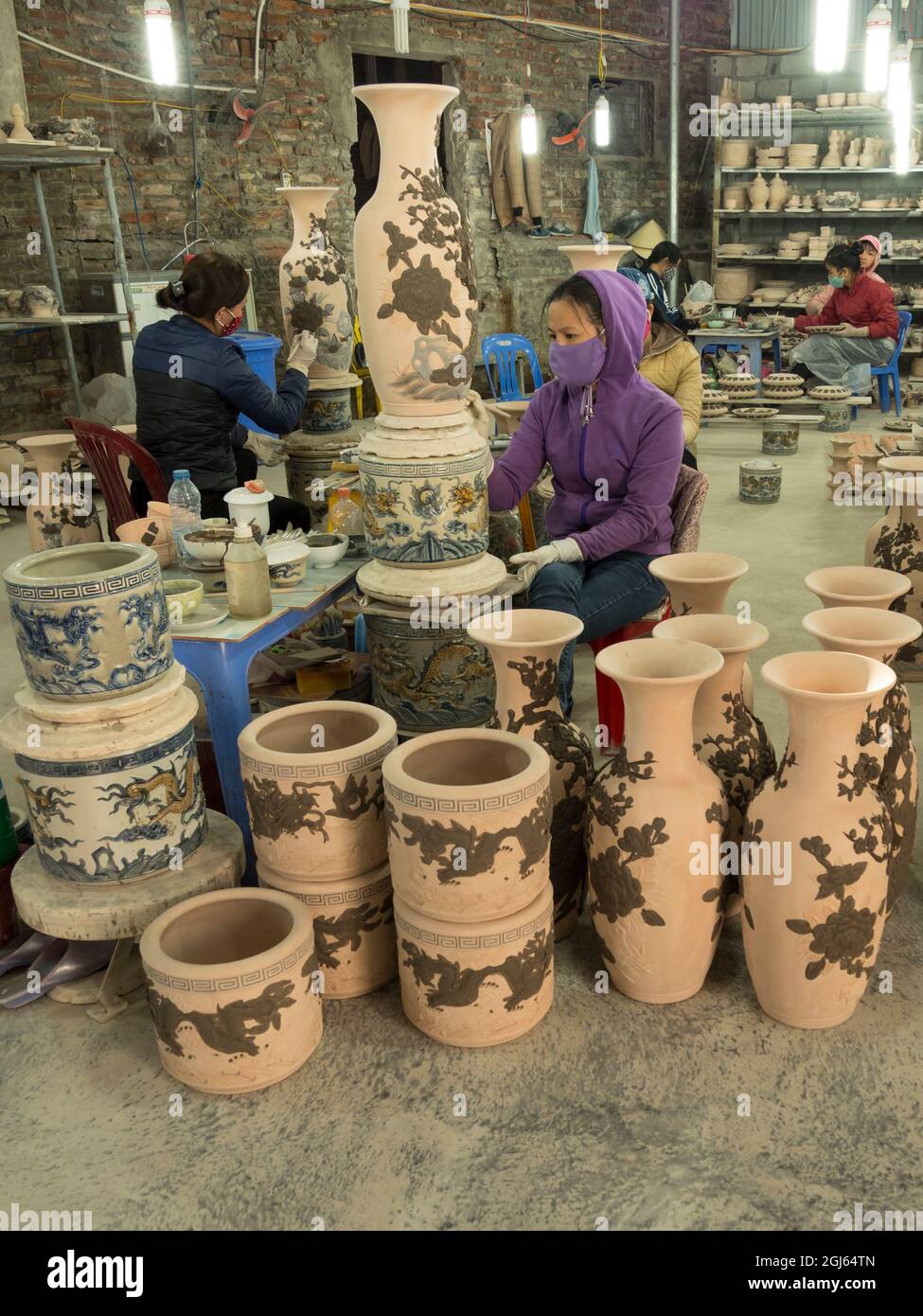 Asia, Vietnam, Phu Lang pottery village. Woman decorating a large vase ...
