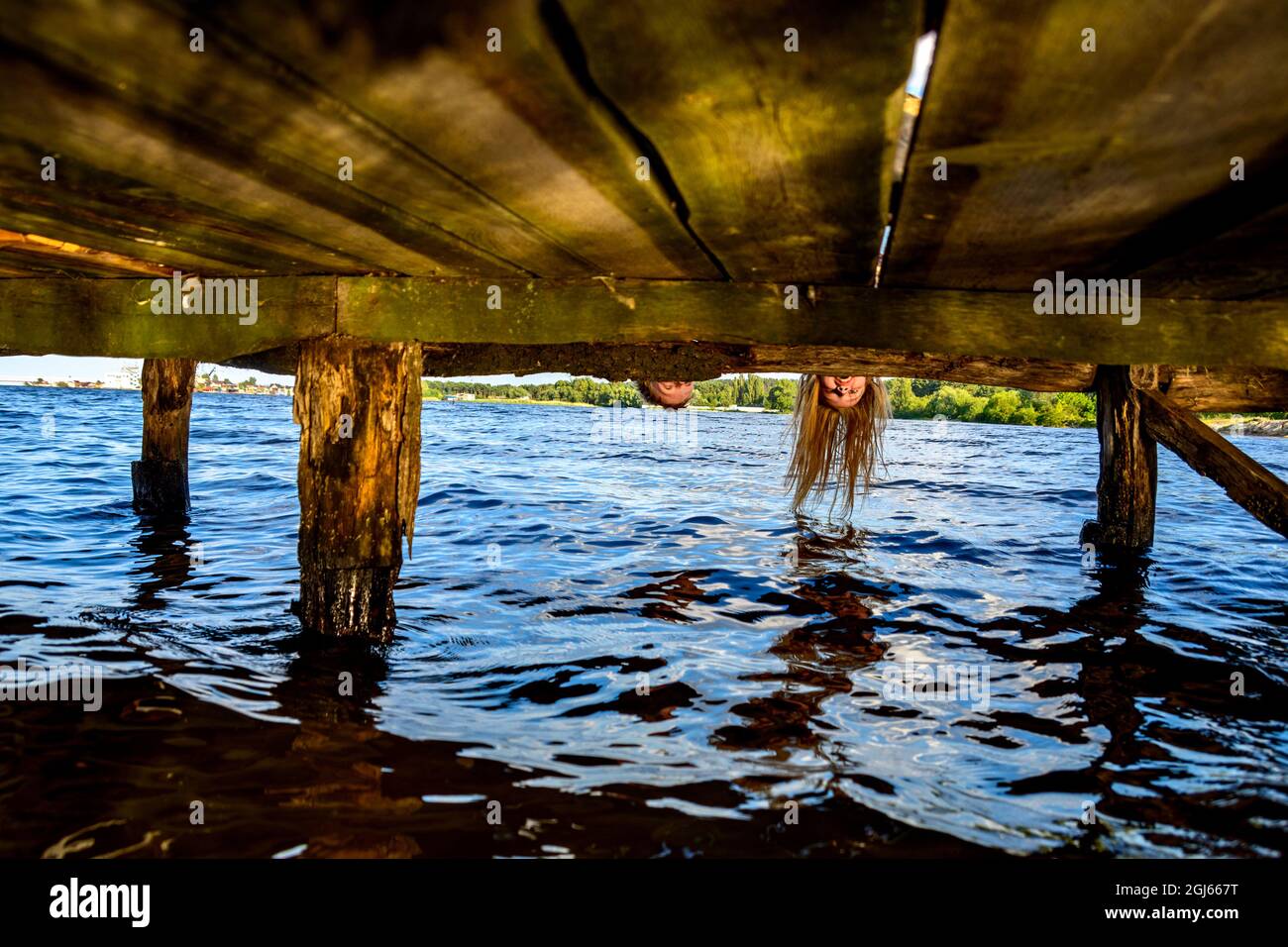 Children look out from under the wooden bridge above the water Stock ...