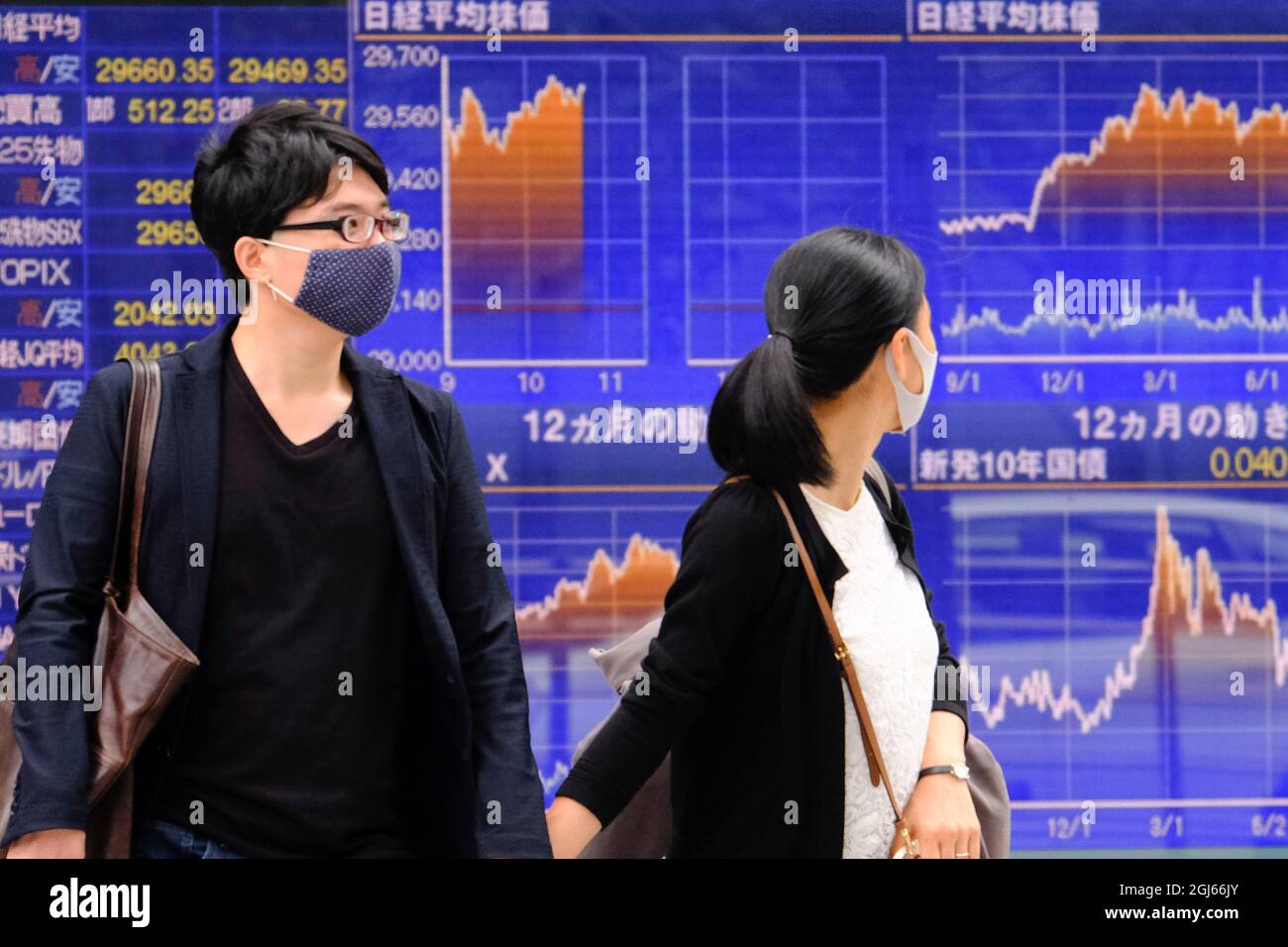 People wearing walk away from an ic board showing stock market indexes ...