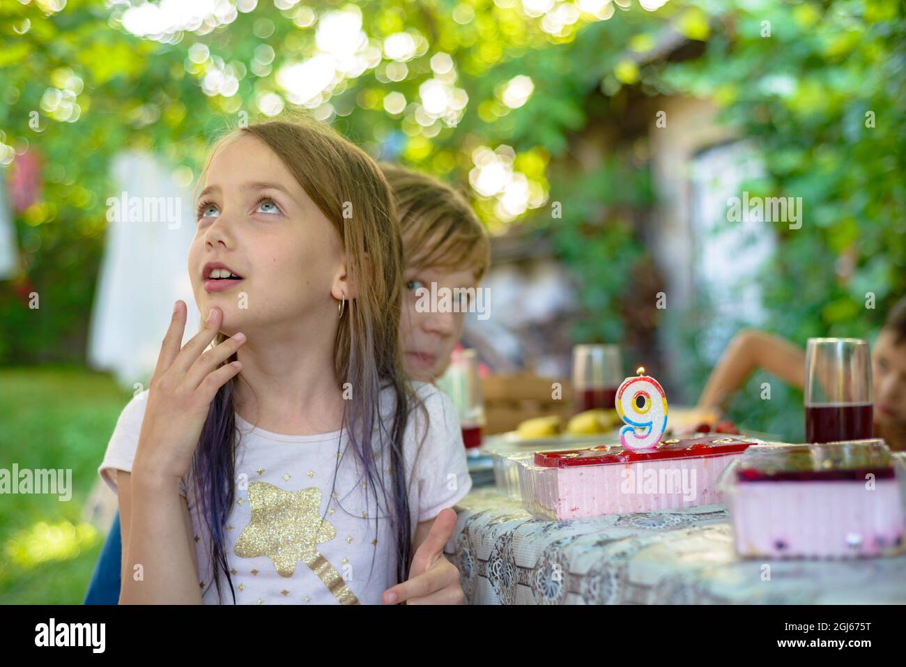 The girl makes a wish for her birthday. The child is 9 years old Stock ...