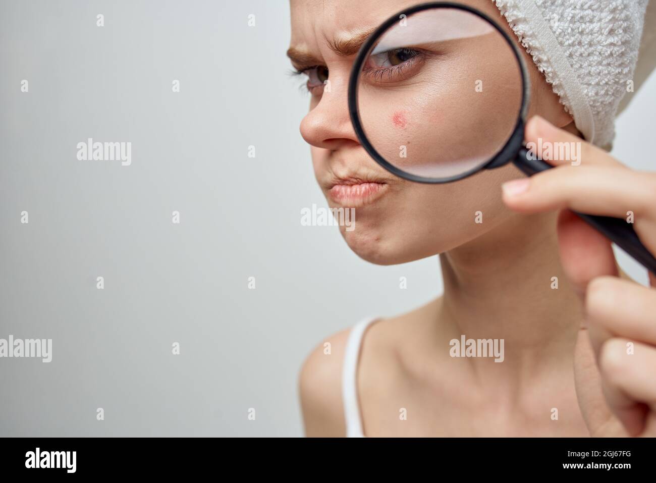 pretty woman with a magnifying glass in hand skin problems close-up ...
