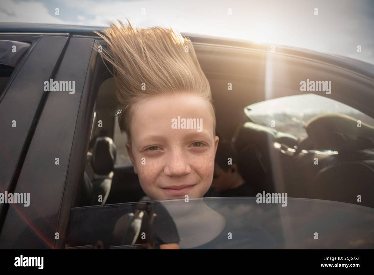 The boy travels in the car. The wind ripples the boy's hair in the car ...
