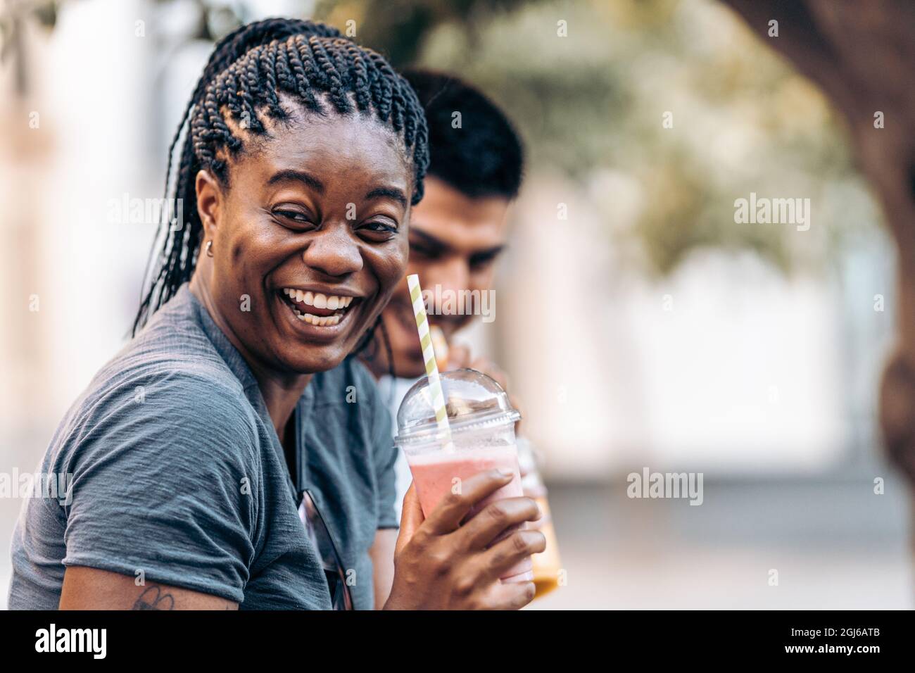 Afro young woman laughing while drinking a shake with a caucasian man ...
