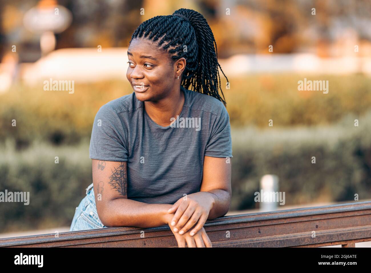 Distracted afro woman with summer clothes leaning on a rail in the ...