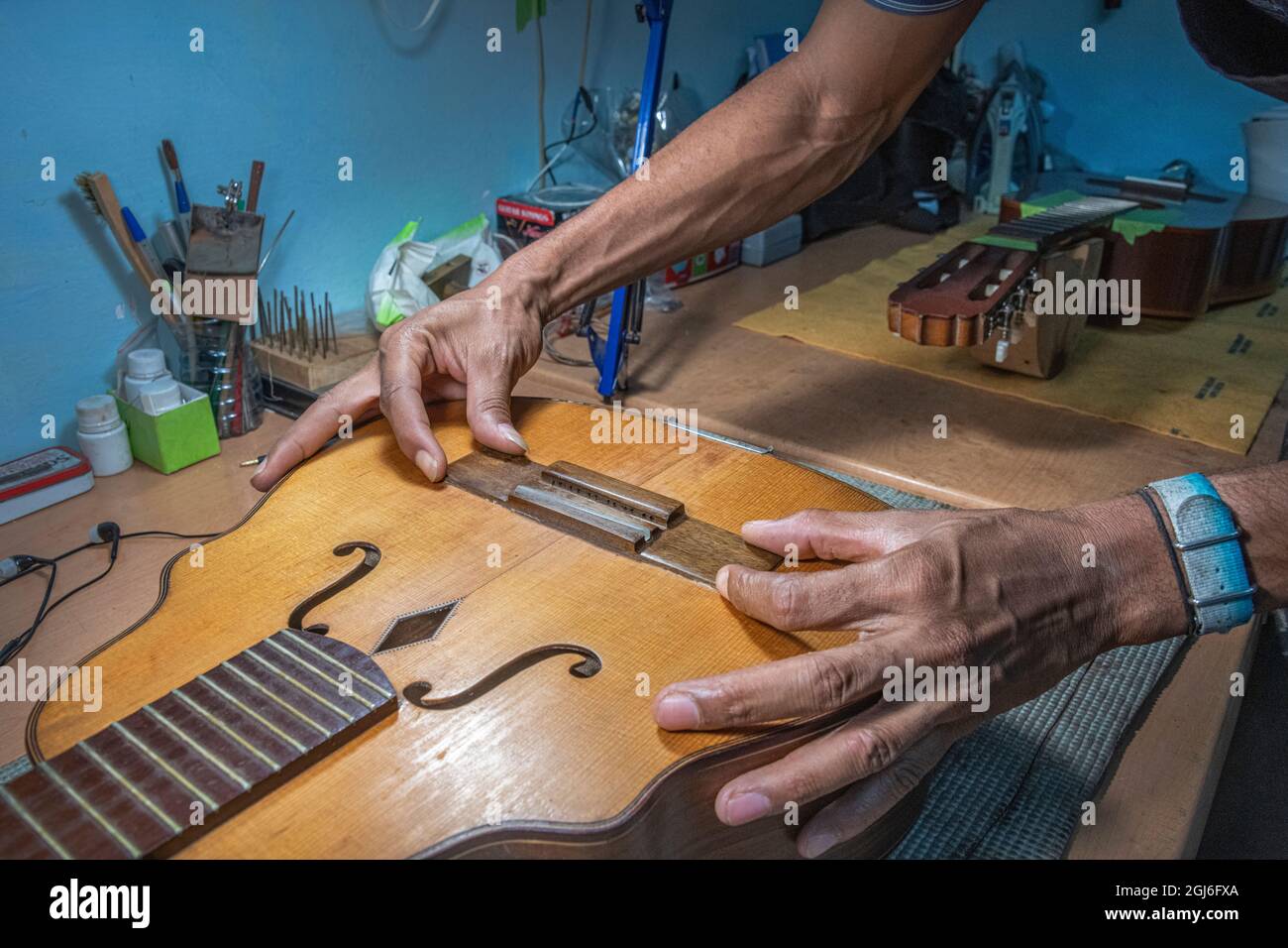 Close-up of craftsman's hands applying parts to a guitar in string ...