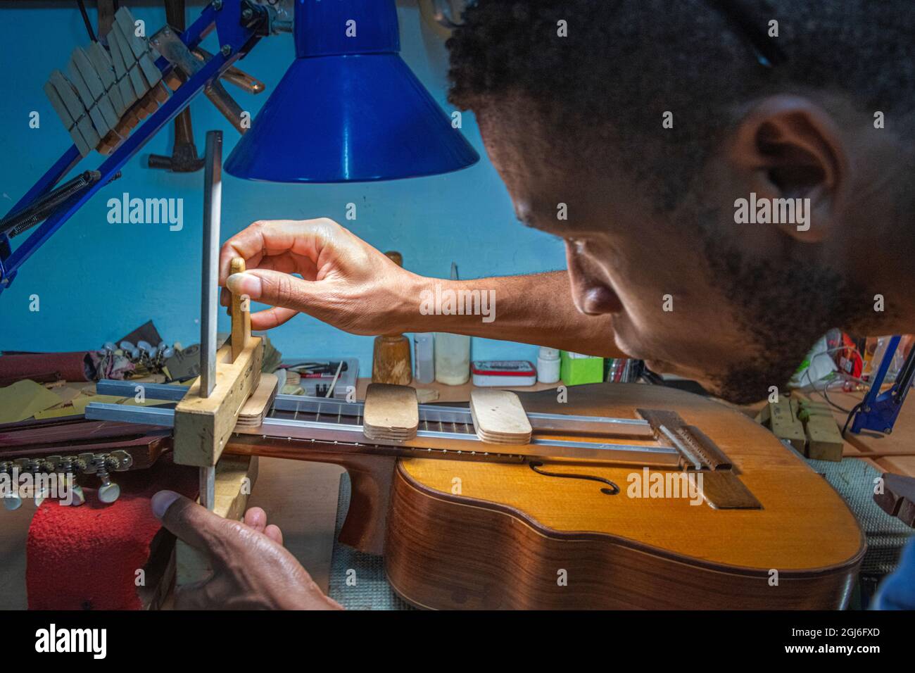 Close-up of craftsman fixing a guitar in a string instrument repair ...