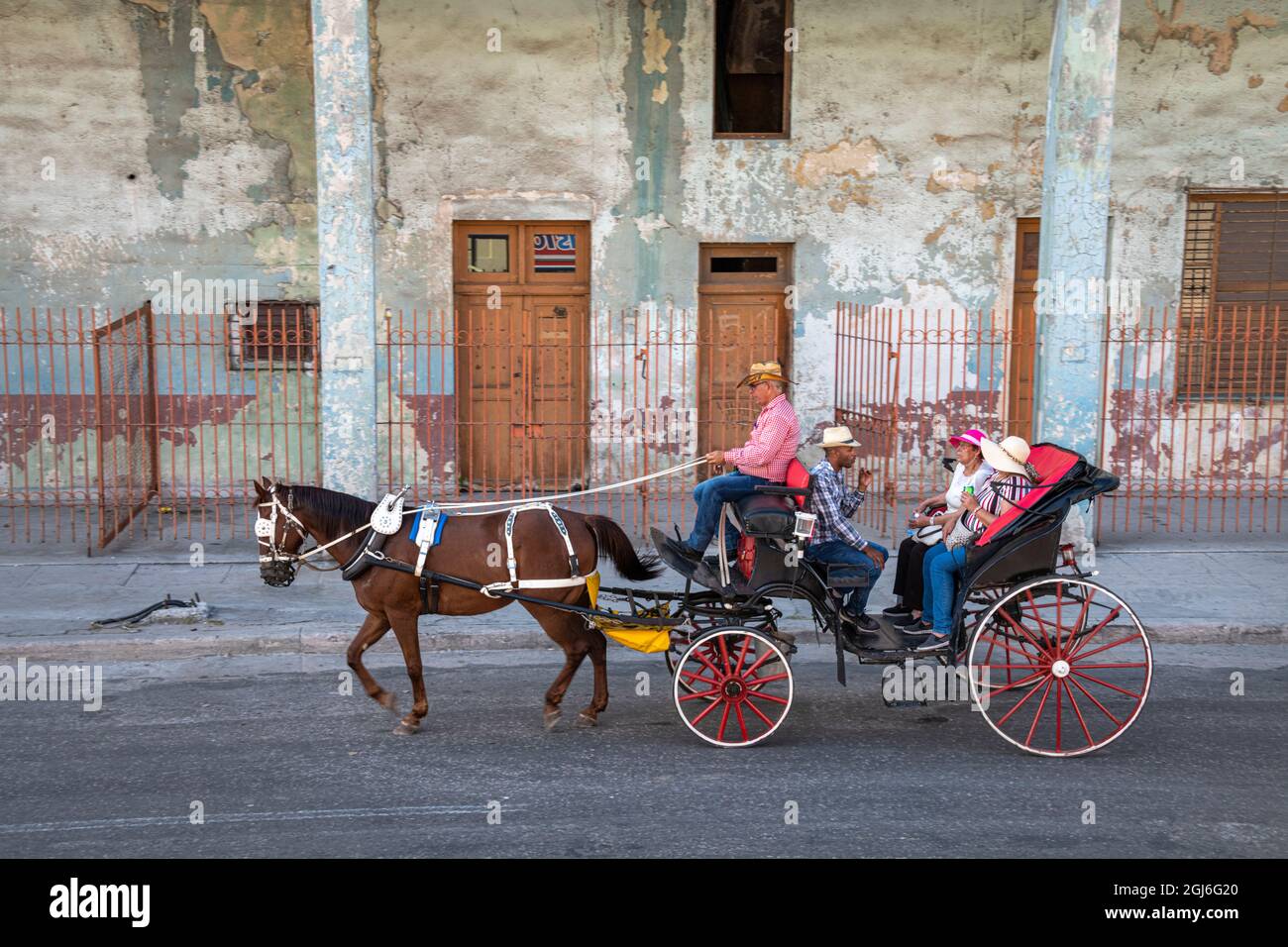 Tourists in horse-drawn carriage in front of crumbling building on Old ...