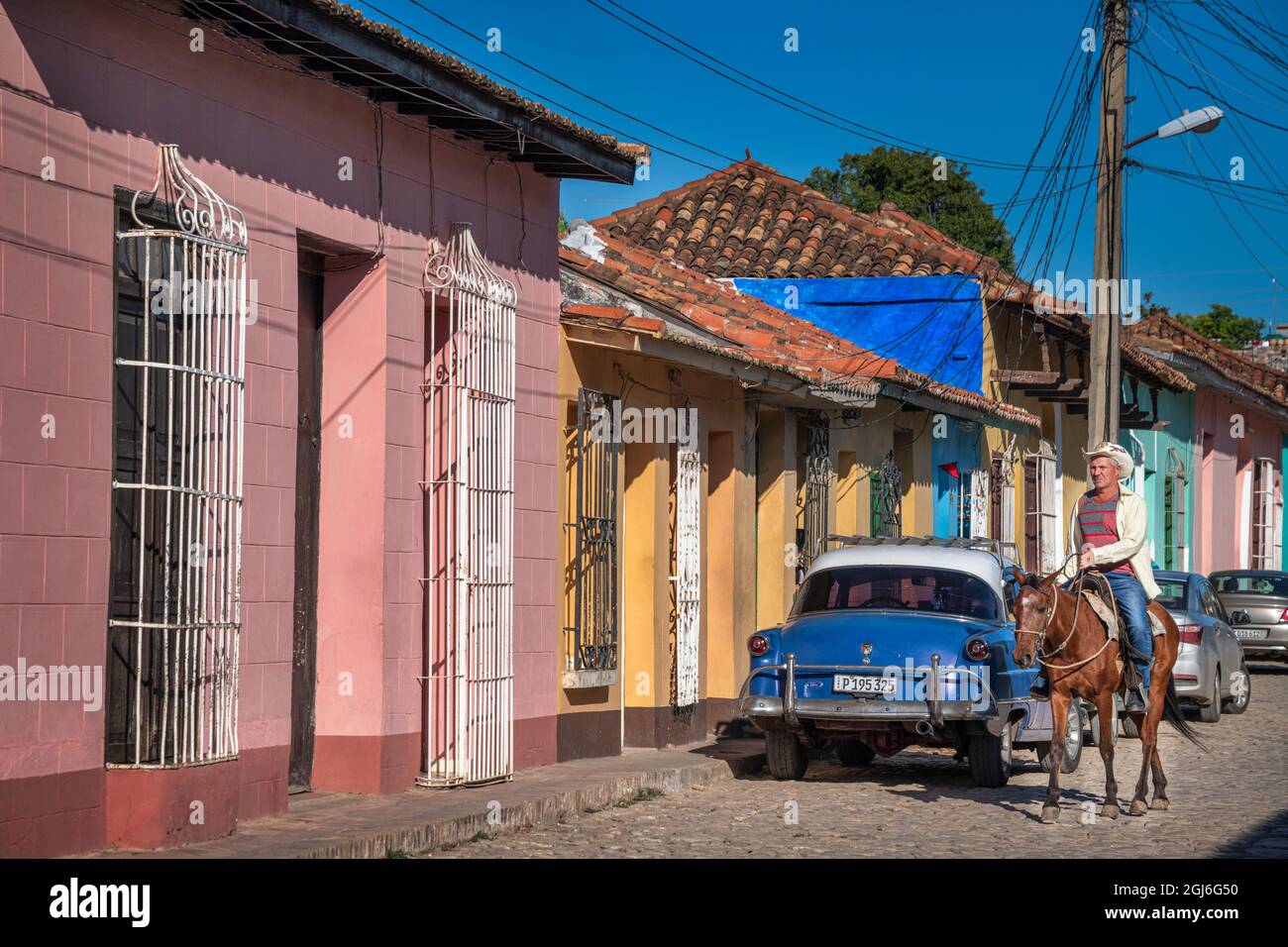 Cowboy on horse riding next to classic car in Trinidad, Cuba Stock ...