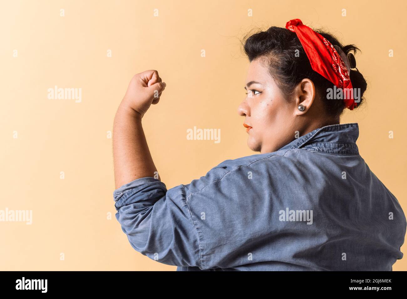 Strong plus size Hispanic woman with a clenched fist rolling up her ...