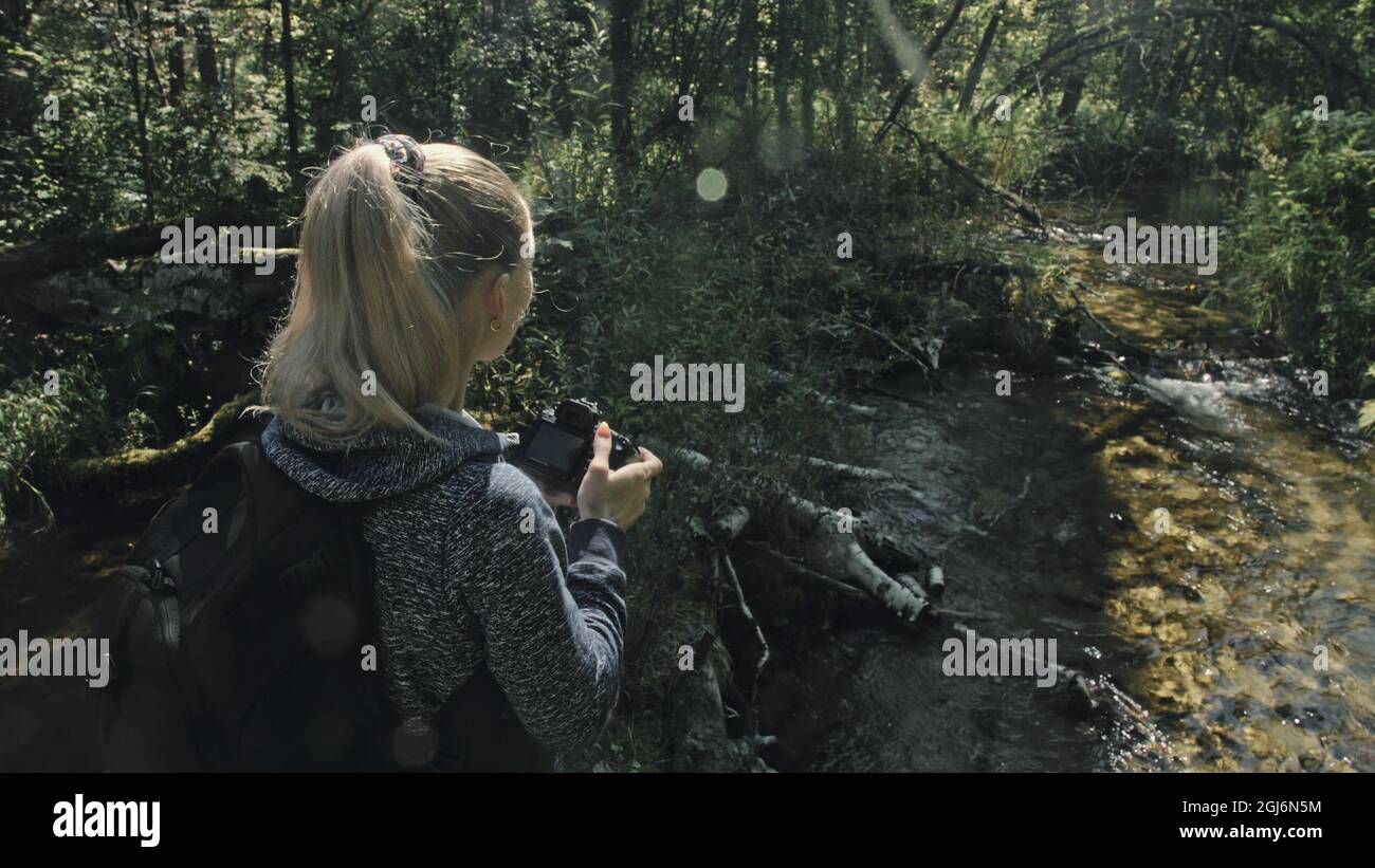 Traveler photographing scenic view in forest river. Wood bridge fallen ...