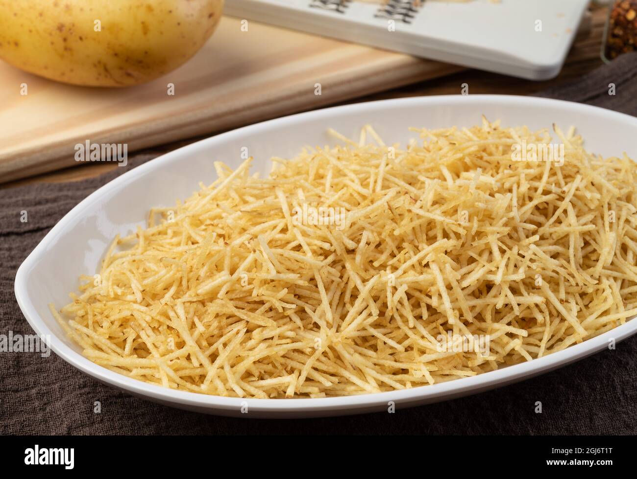 Potato straw or shoestring potato in a white plate with raw potatoes ...