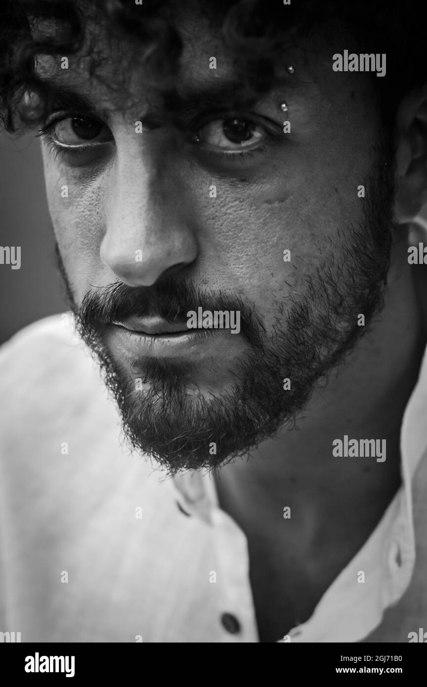 Black and white portrait of a young man with beard and curly hair who ...