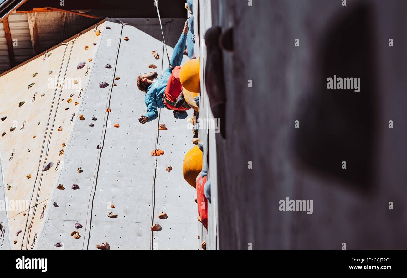Young man professional rock climber practicing at training center in ...