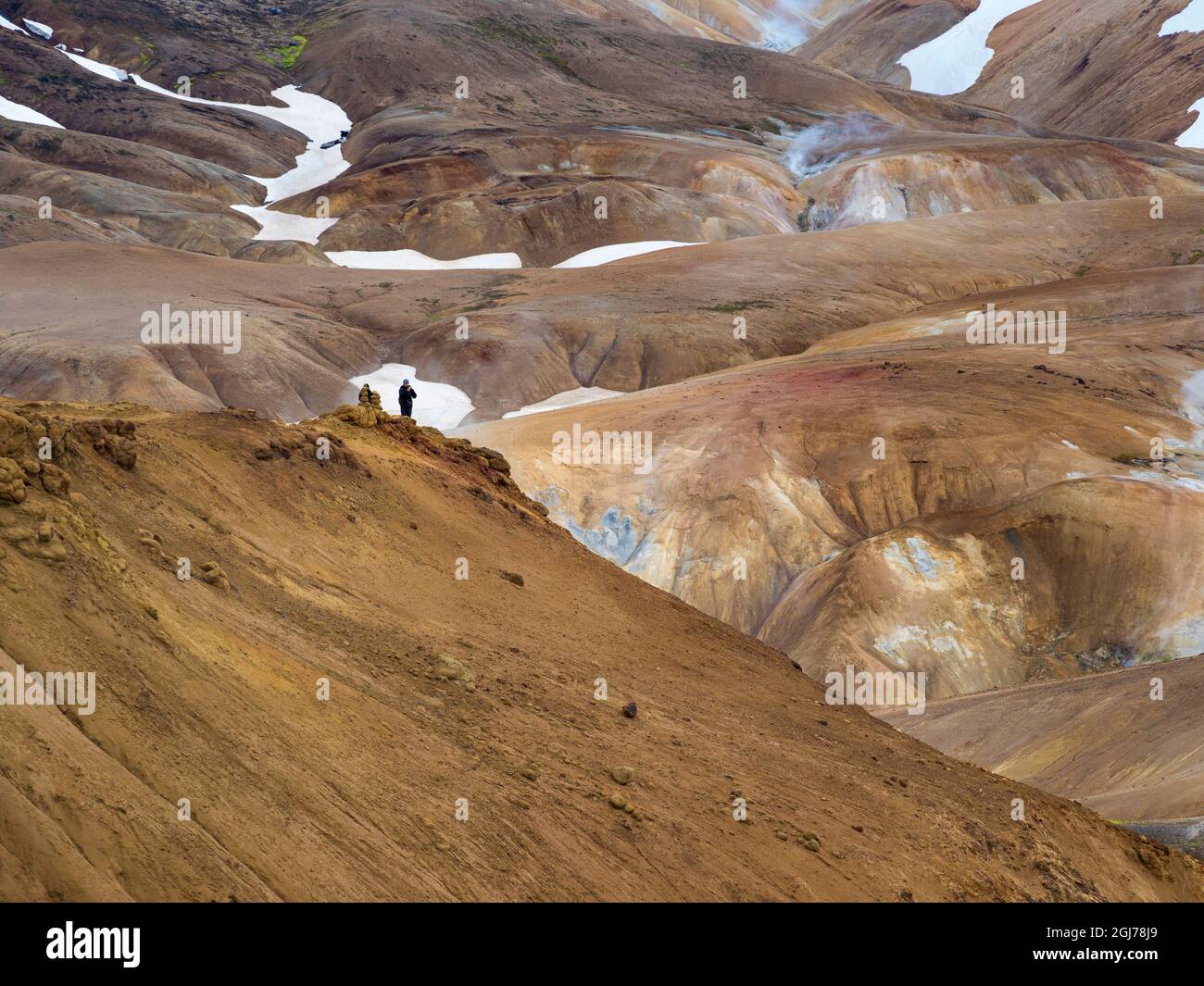 Hikers in the geothermal area Hveradalir in the mountains ...