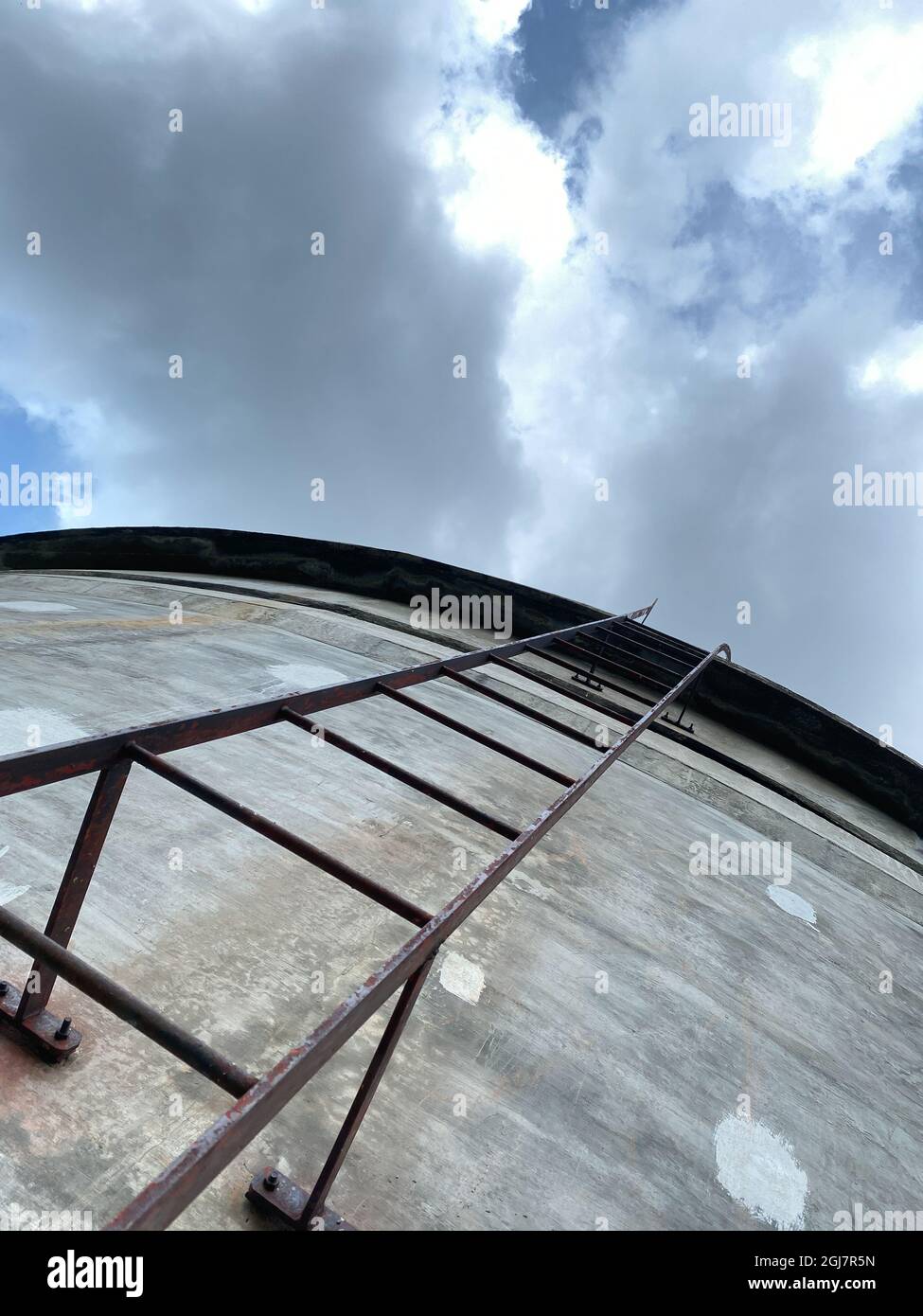 View looking up a rusted steel ladder going up a concrete water tank ...
