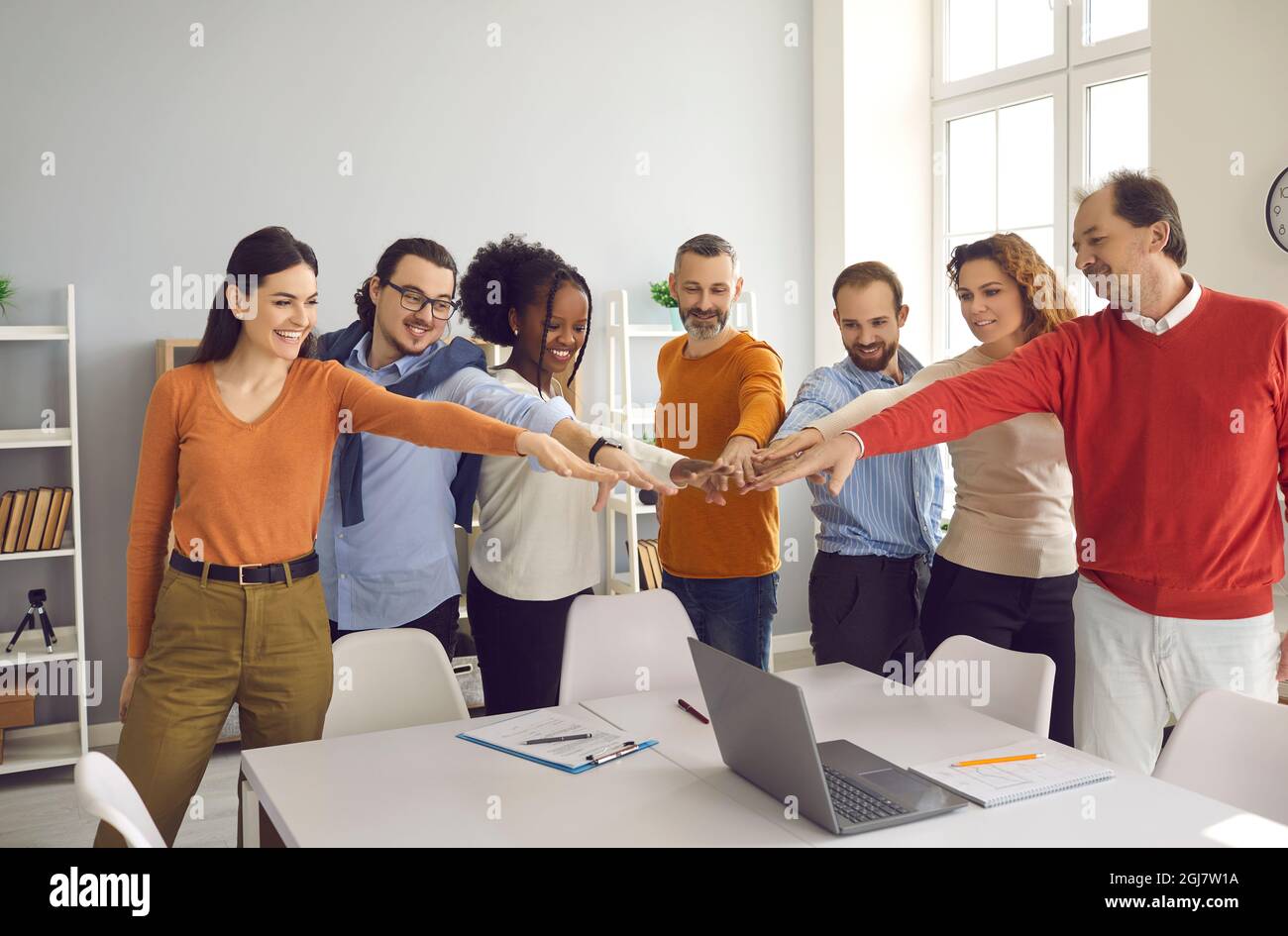 Happy diverse team of enthusiastic business people joining hands in ...