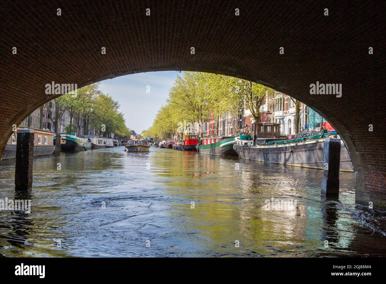 Europe, Netherlands, Amsterdam. Canal looking through arched bridge ...