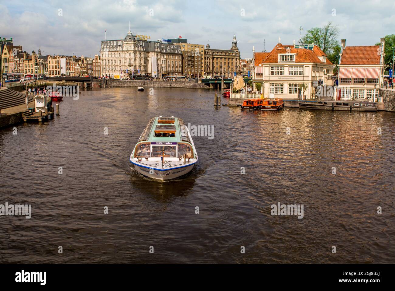 Tour boat in the Oosterdok with the Victoria Hotel in background ...