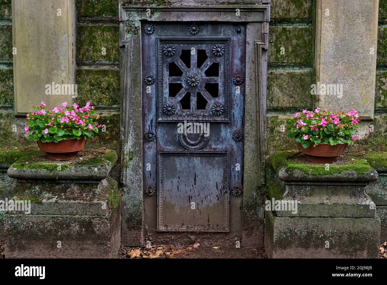 Old, weathered and mossy stone crypt with two flower pots beside the ...