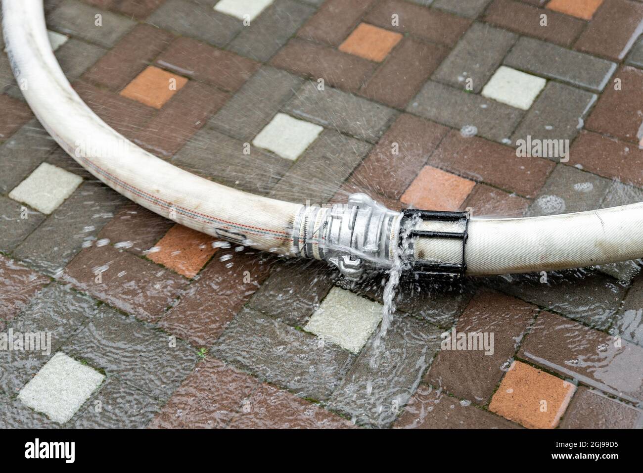 Close-up old worn out broken fire hose leaking with high pressure water ...