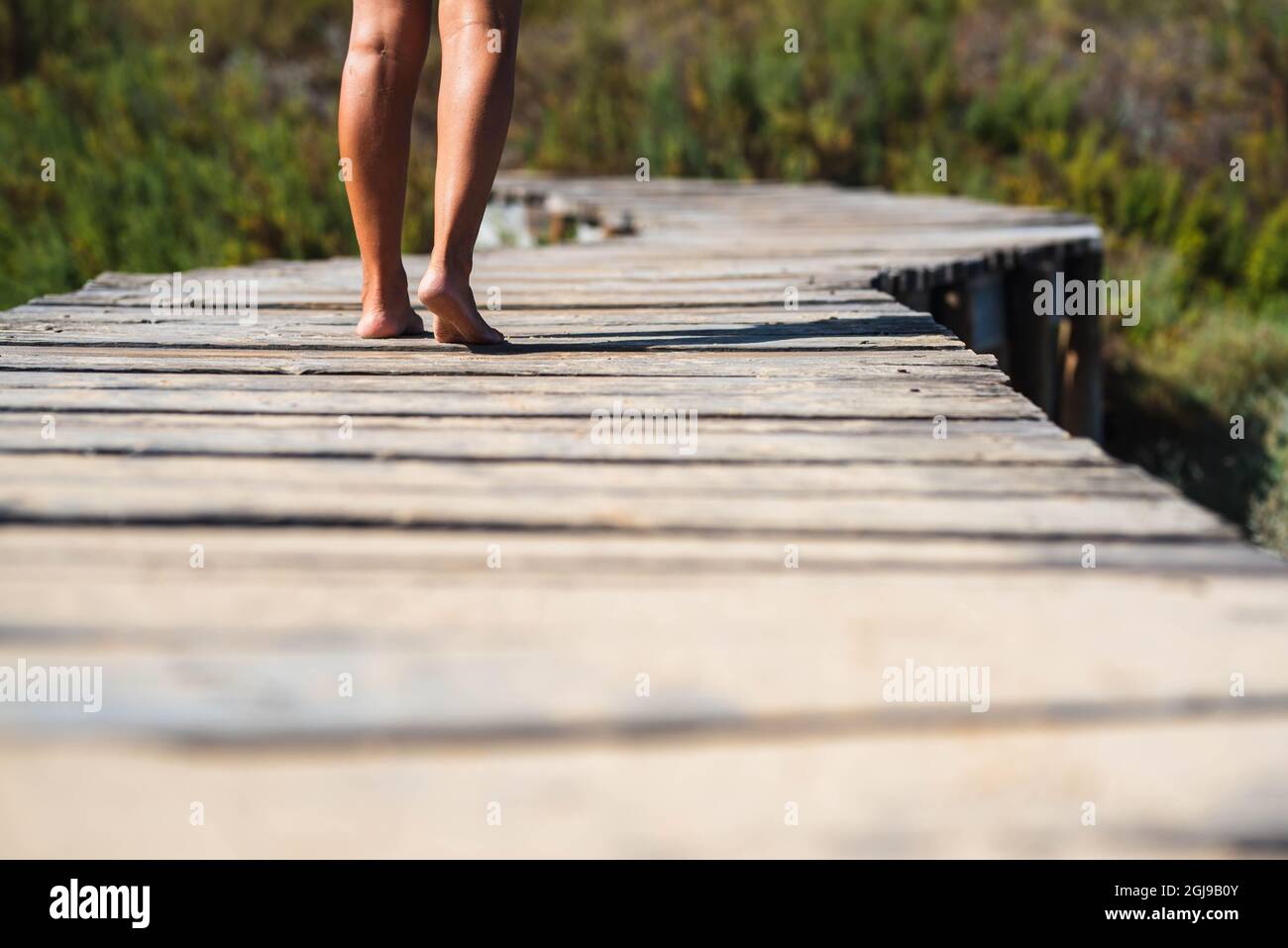 Low section legs of woman walking barefoot on elevated footbridge ...
