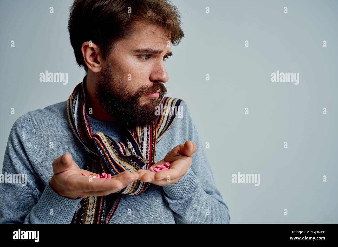 bearded man treating the disease with pills in hands light background ...