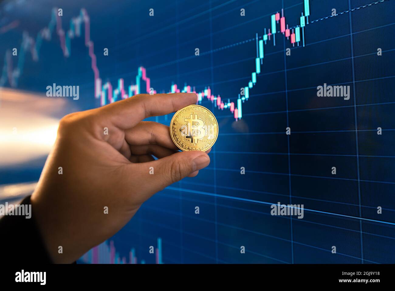 Bitcoin coins in hand in front of the computer and bitcoin graph Stock ...