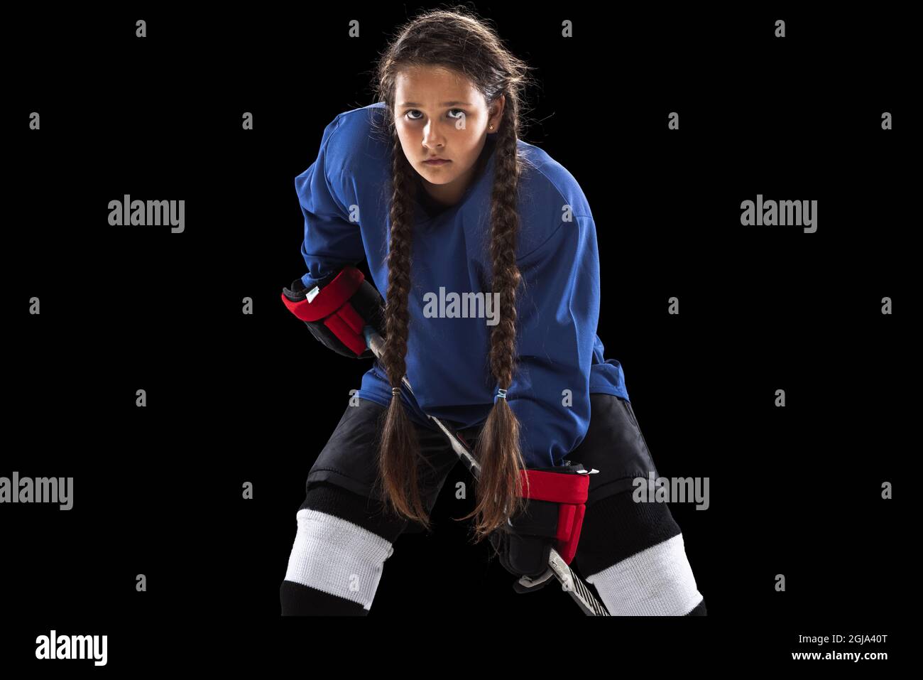 One young girl hockey player training isolated over black background ...
