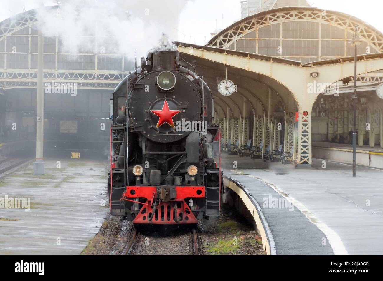 Retro steam train departs from the railway station with the clock on ...