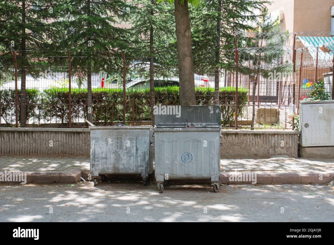 Garbage containers under trees on a roadside in Istanbul. Space for ...