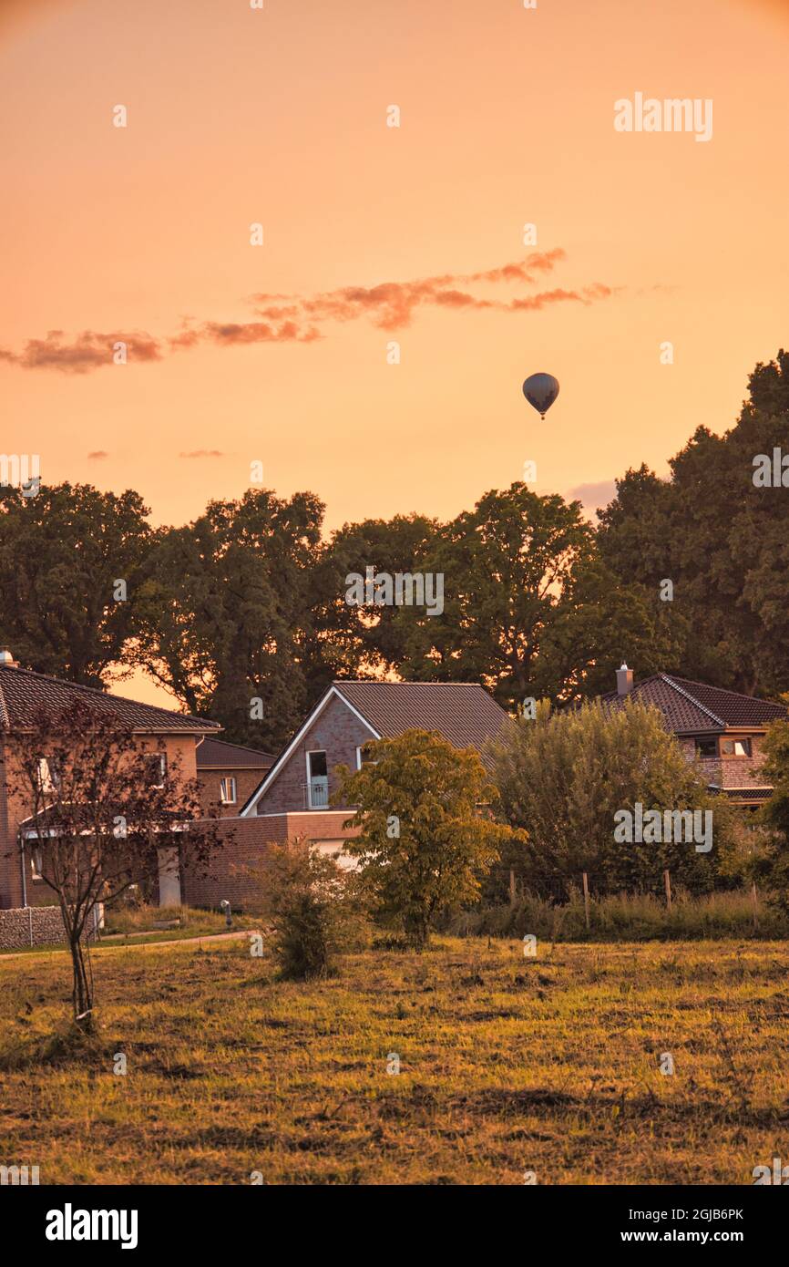 Vertical shot of a hot air balloon in a beautiful bright orange sunset ...