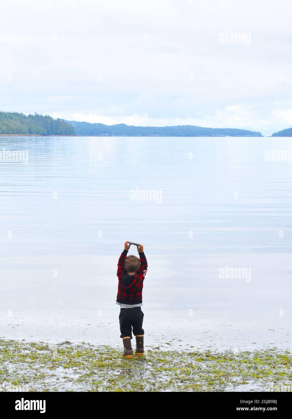 Alaska, Ketchikan, 2 year old boy throwing rocks in ocean Stock Photo ...