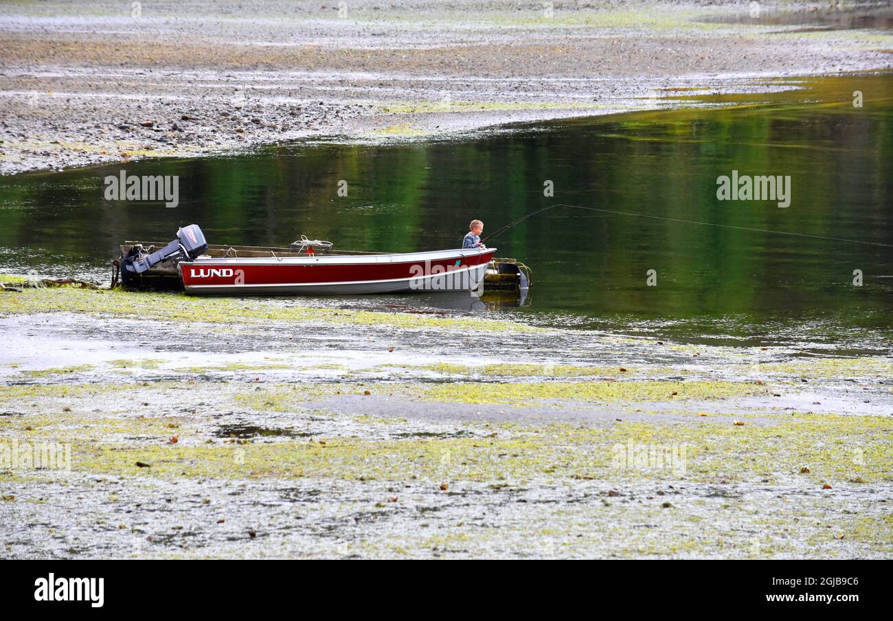 Alaska, Ketchikan, boy fishing from skiff at low tide. (MR Stock Photo ...