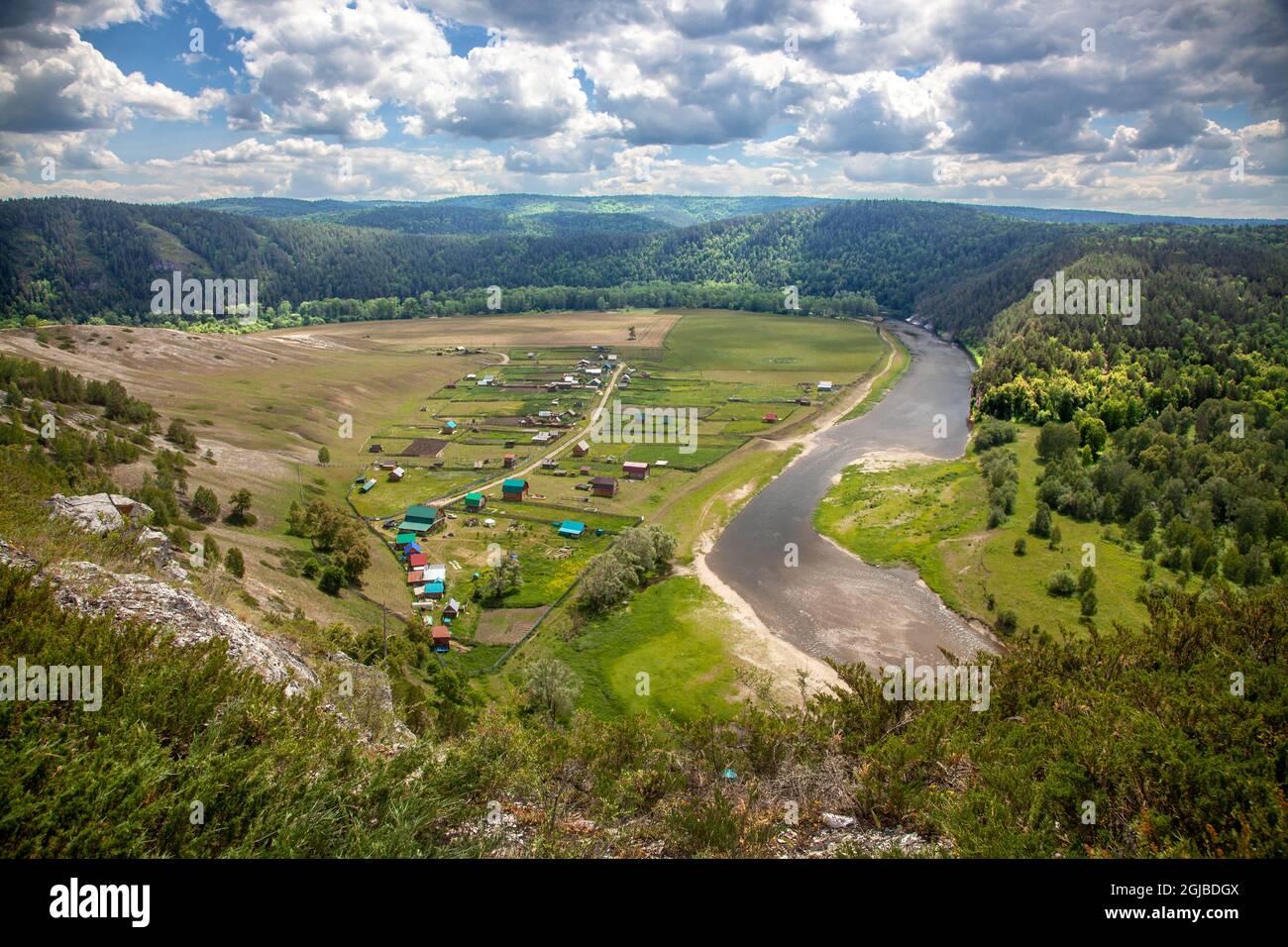 Aerial angle shot of Belaya river with a village in the valley in ...