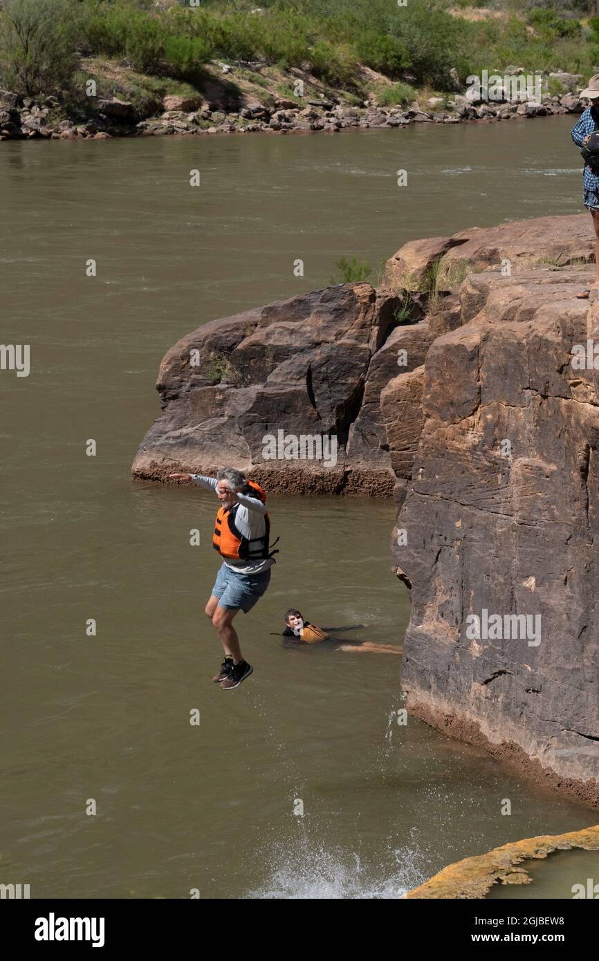 USA, Arizona. Hiker jumping from cliffs into river near Pumpkin Springs ...