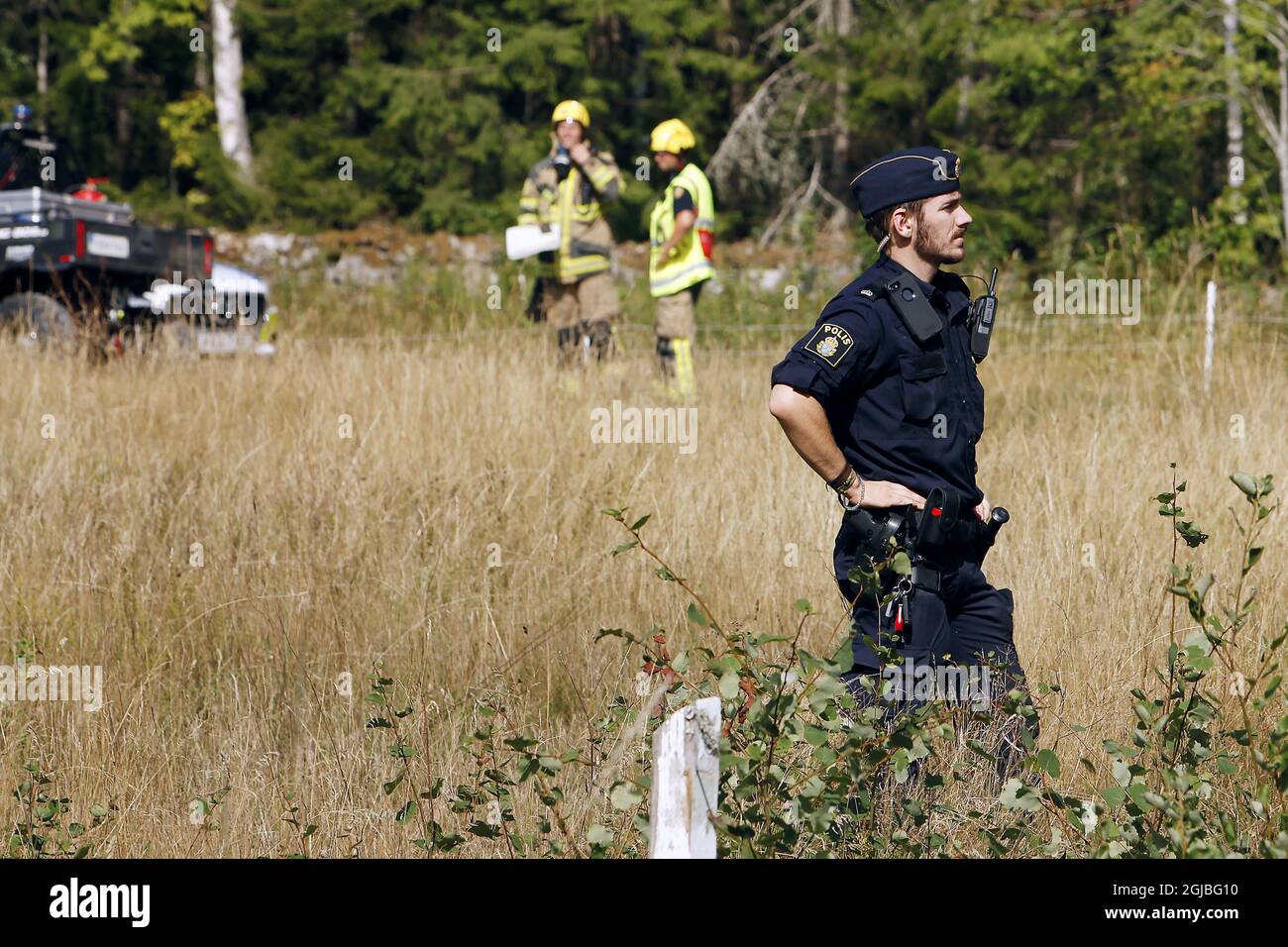 Firefighters and police stand near the site where a JAS 39 Gripen ...