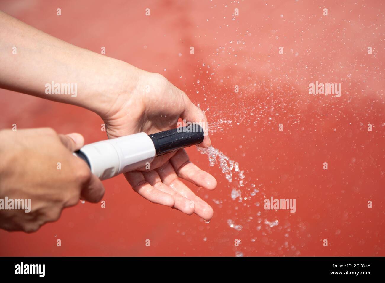 Selective of a water hose in hands wetting red terrace floor Stock ...