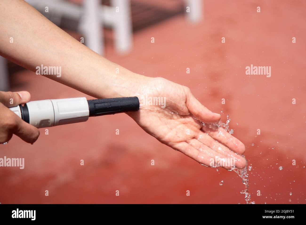 Selective of a water hose in hands wetting red terrace floor Stock ...
