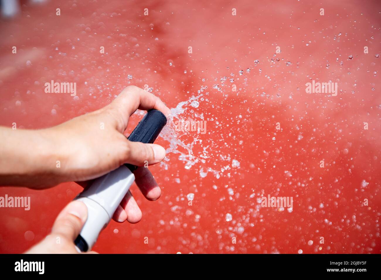 Selective of a water hose in hands wetting red terrace floor Stock ...