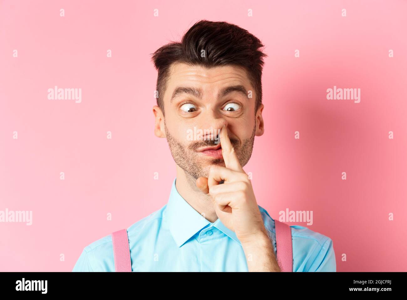 Image of funny caucasian guy picking nose and squint eyes, making dumb ...