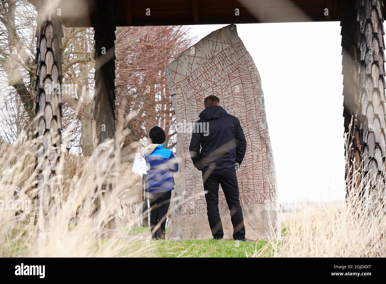 A father and a son look at the Viking-era Rok runestone near the Lake ...