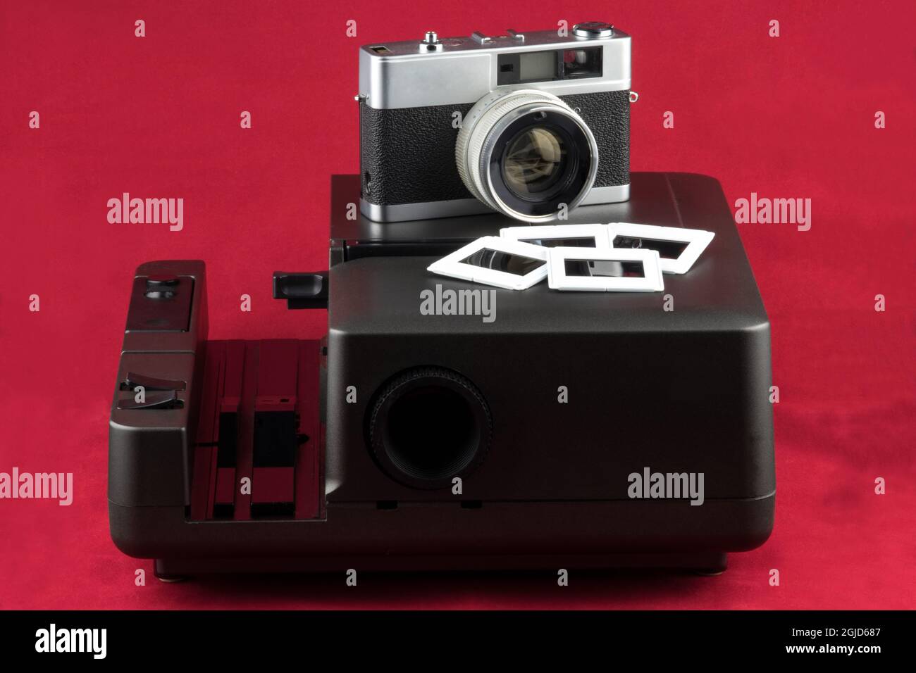 Old film camera with slide projector and slides on a red background ...
