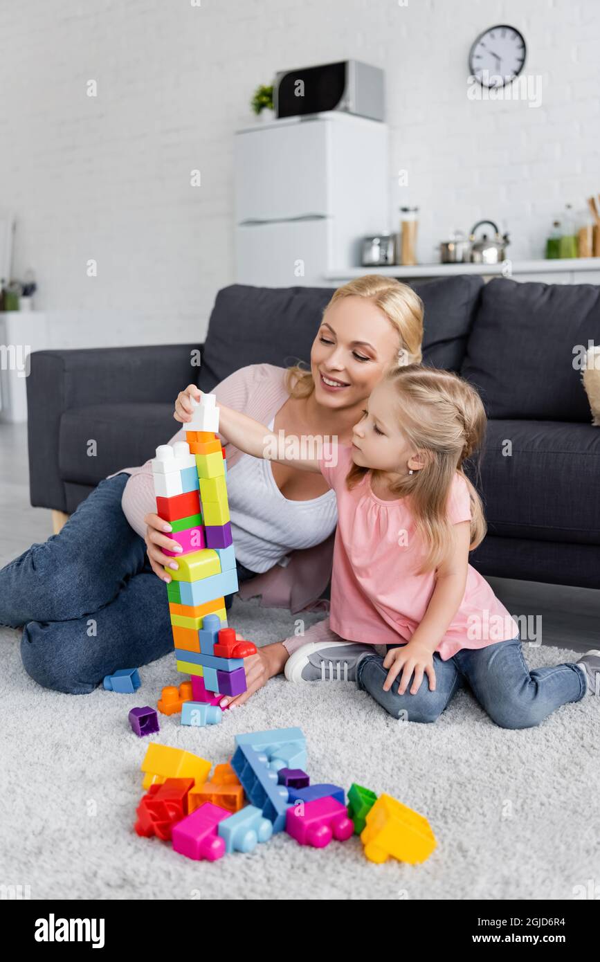 girl making tower of colorful building blocks near happy mom Stock ...