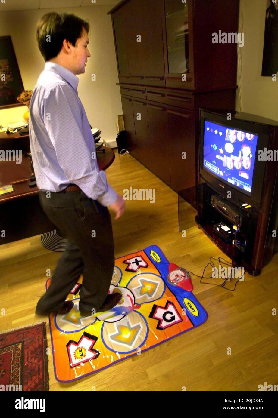 A man uses a Dance Dance Revolution video game and carpet connected to ...
