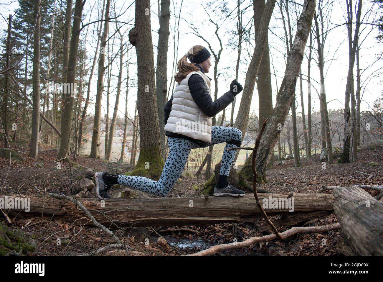 A girl stretching and balancing on a log after a run. Photo: Henrik ...