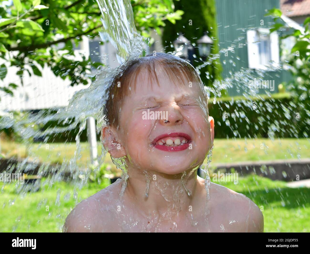 STOCKHOLM 20200624 7-year-old Melcher, gets a cold shower in the garden ...