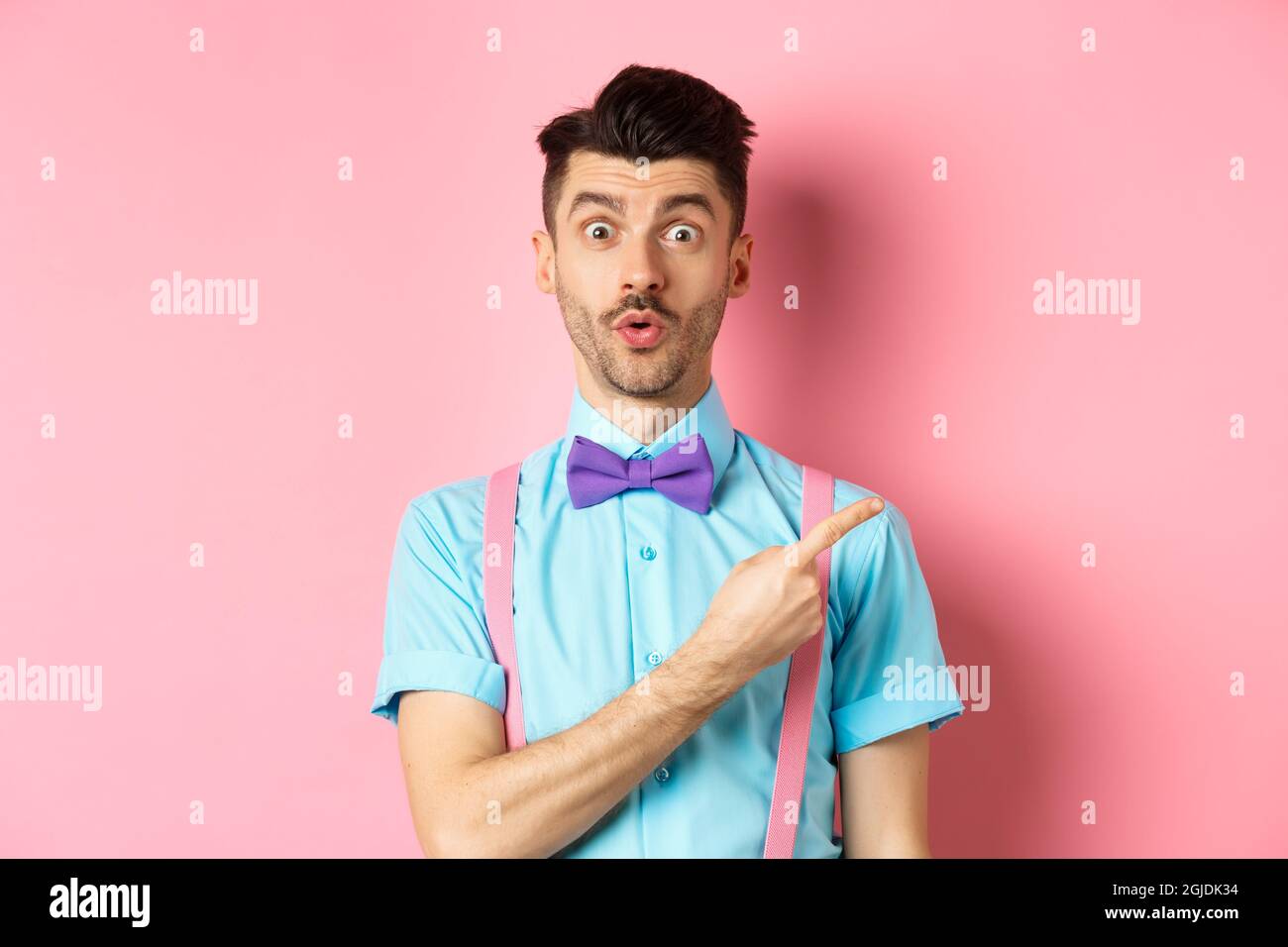 Intrigued and surprised cute guy with moustache showing awesome promo ...