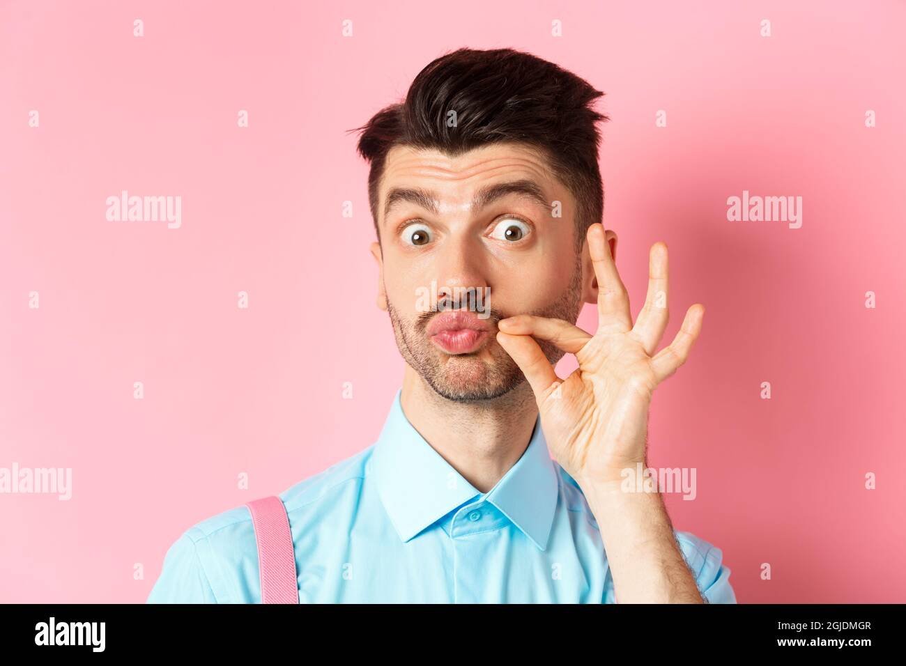 Close up of funny caucasian guy touching his french moustache, pucker ...