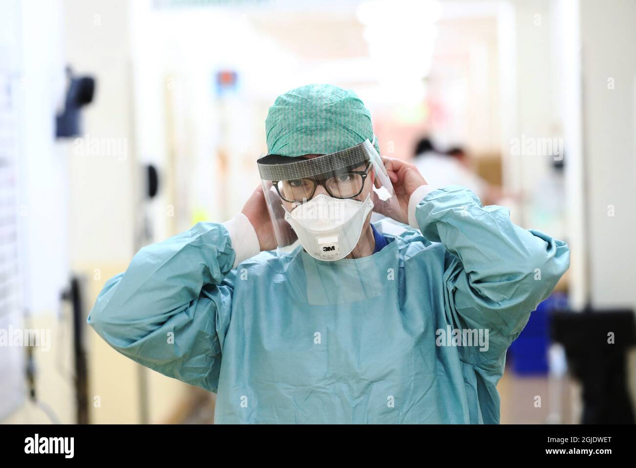 Doctor wearing personal protective equipment (PPE), visor and face mask ...