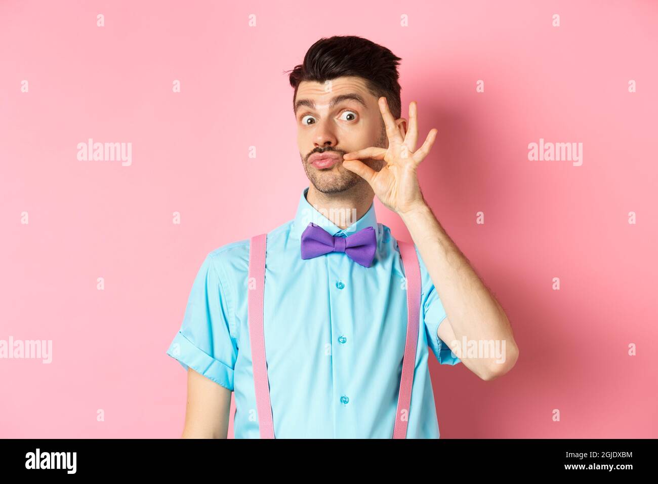 Funny young man touching his french moustache and pucker lips, looking ...